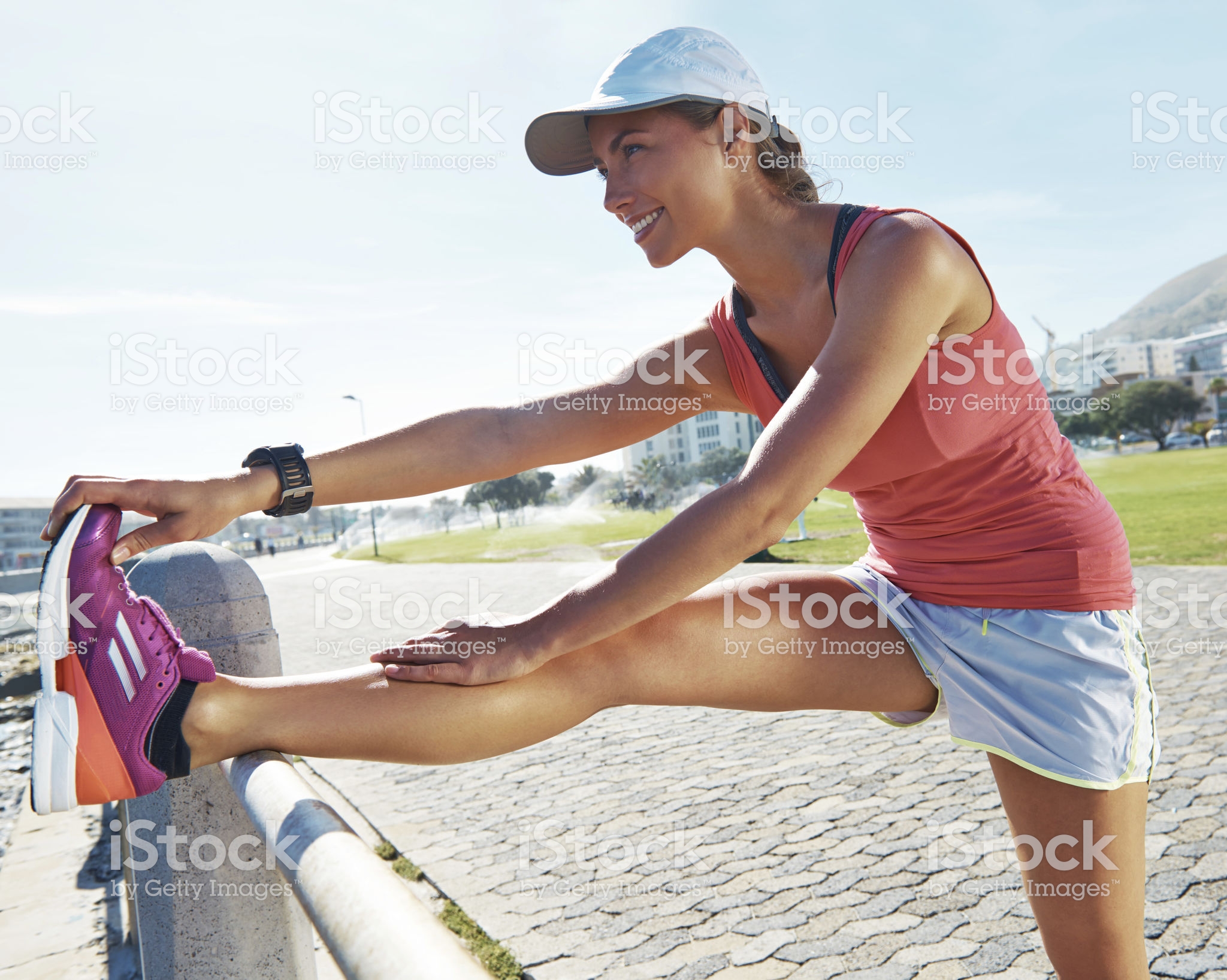 A young female runner stretching her muscles before a training session ...